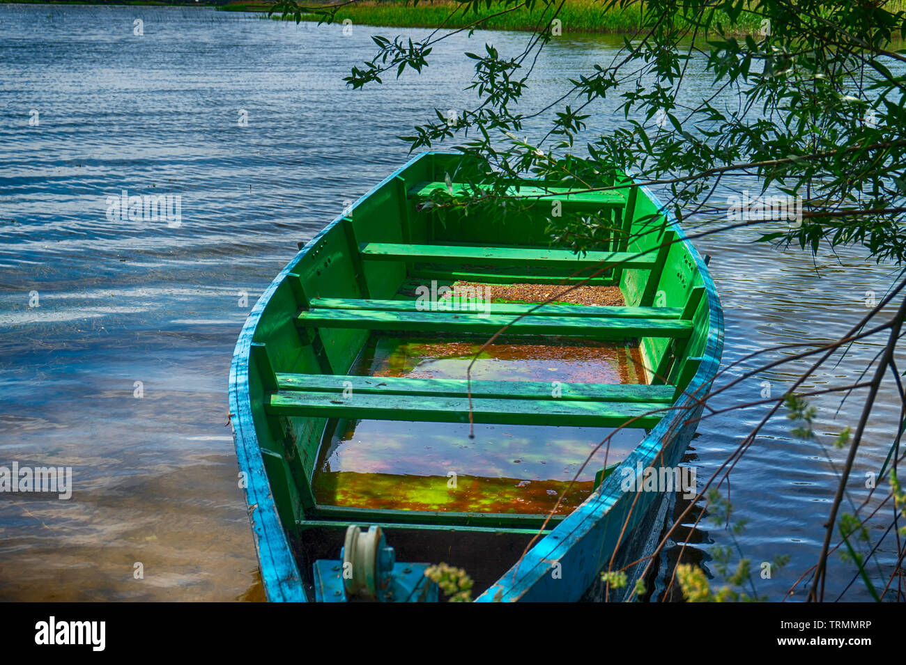 Wooden blue and green dinghy or rowboat full of water moored in the ...
