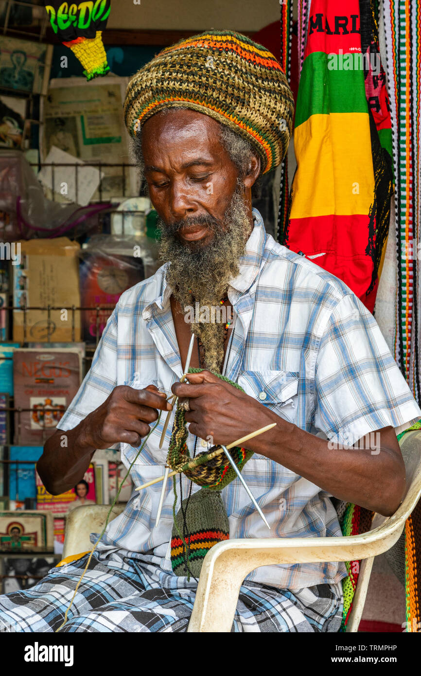 Local shopkeeper knitting a traditional woollen hat either for himself ...