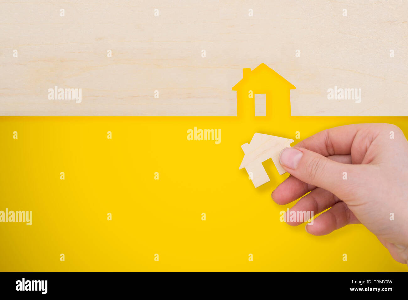 hand places a model house on yellow background Stock Photo - Alamy