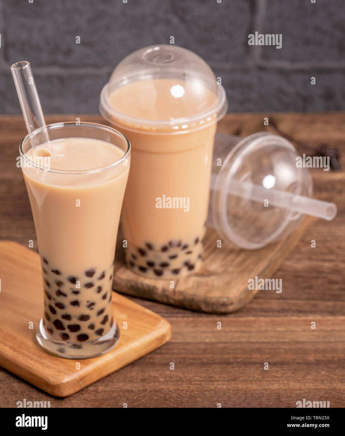 Delicious bubble milk tea with straw in drinking glass on wooden table ...
