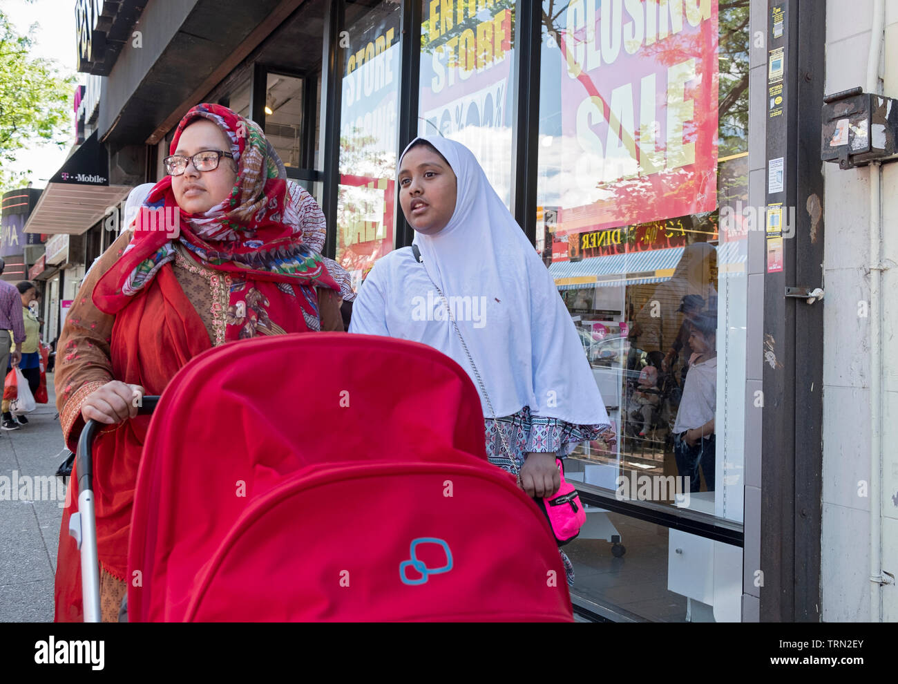 Two Muslim women in hijabs, probably sisters, walk down 74th St. in ...