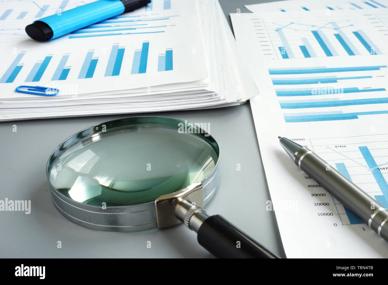 Magnifying glass and business report for auditing Stock Photo - Alamy