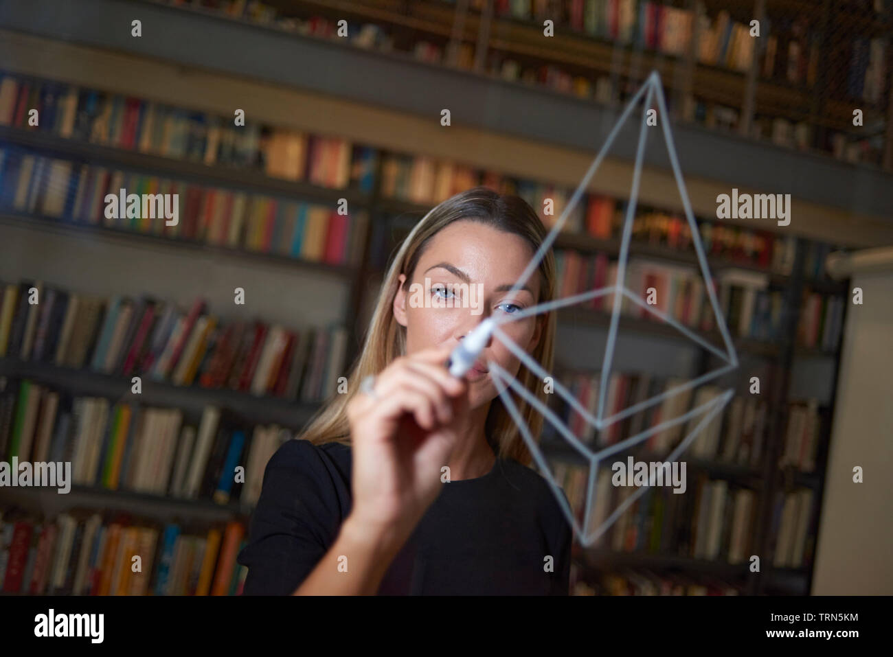 Caucasian female drawing the Ethereum logo on a window and looking in ...