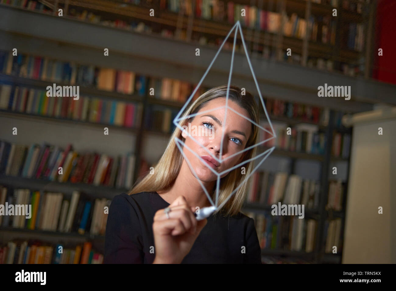 Caucasian female drawing the Ethereum logo on a window and looking in ...