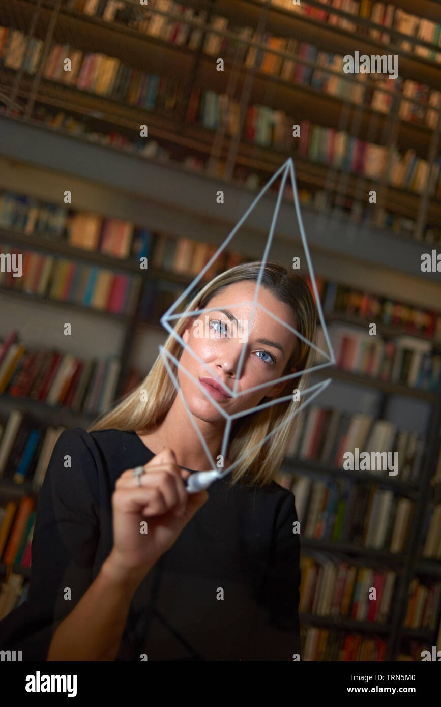 Caucasian female drawing the Ethereum logo on a window and looking in ...