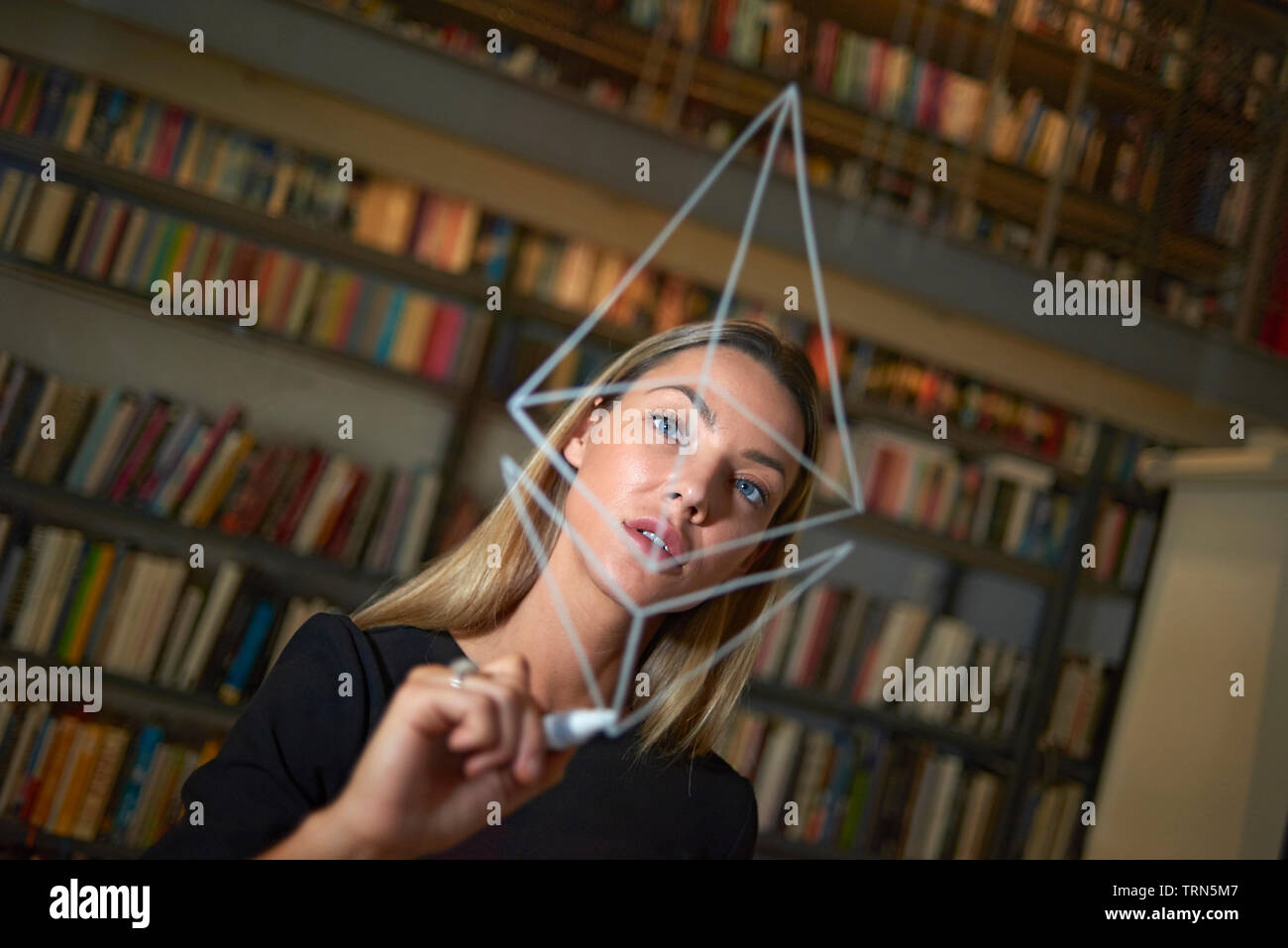 Caucasian female drawing the Ethereum logo on a window and looking in ...