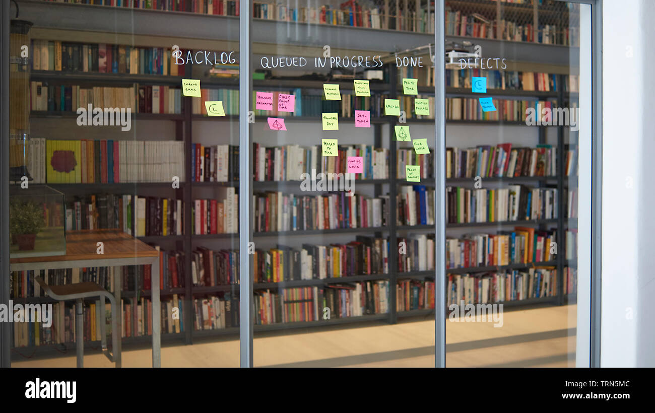 A woman organizing post-it notes on a window in the office making a ...