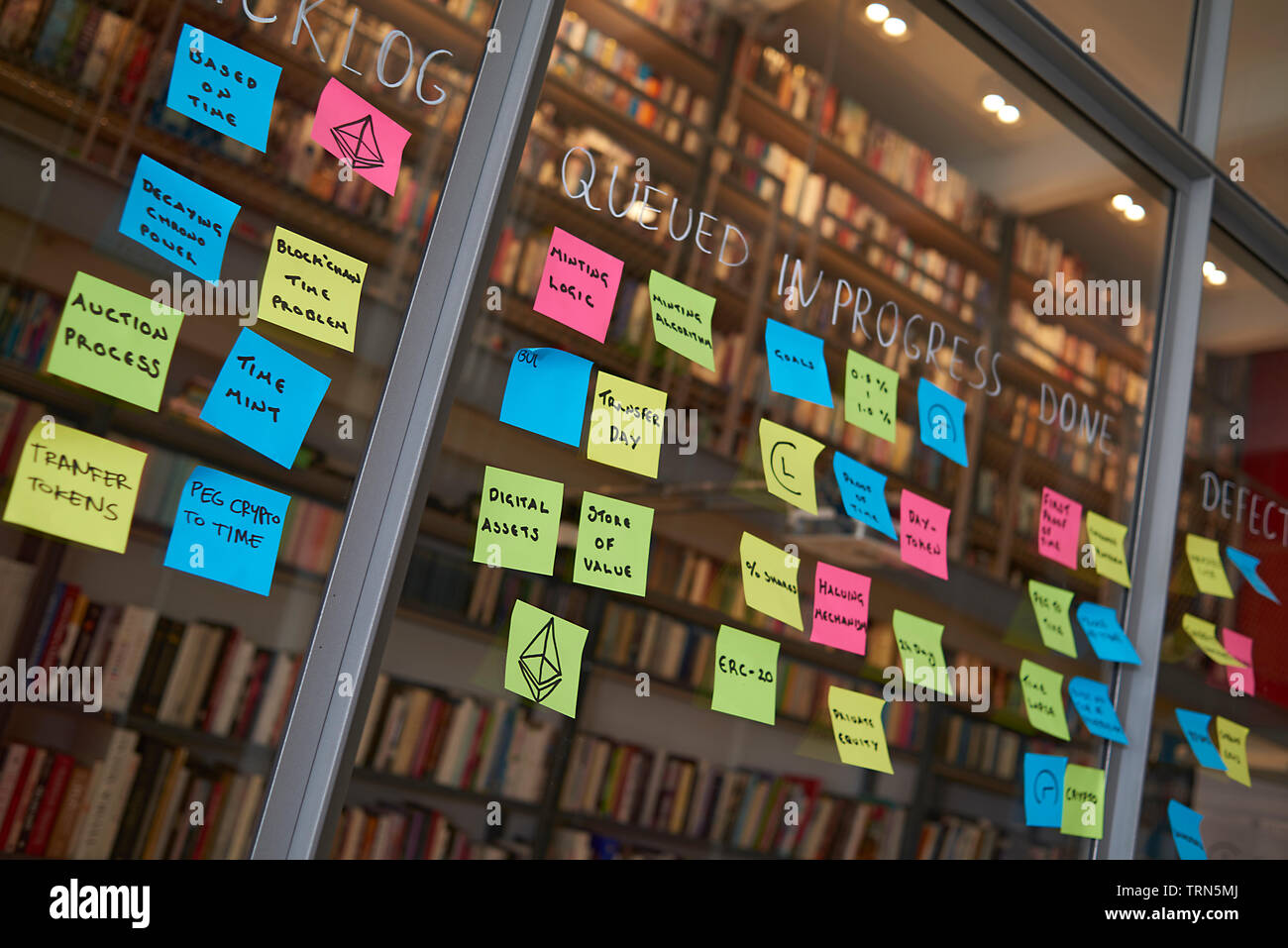 A woman organizing post-it notes on a window in the office making a ...