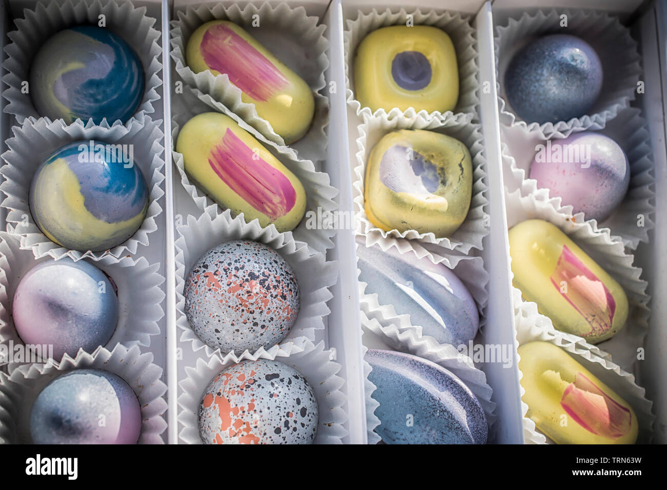 A box of assorted pralines in pastel colors Stock Photo - Alamy