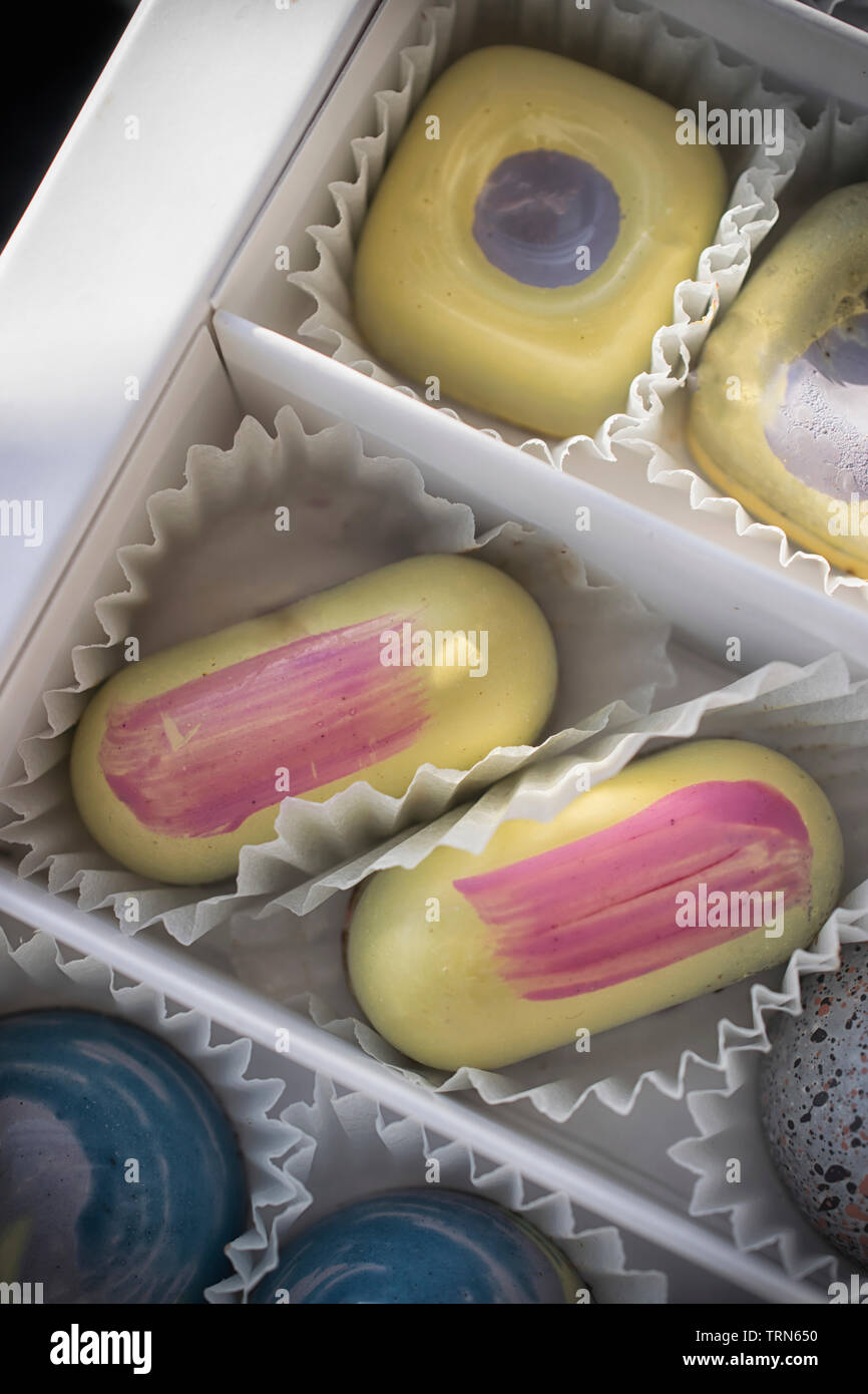 A box of assorted pralines in pastel colors Stock Photo - Alamy