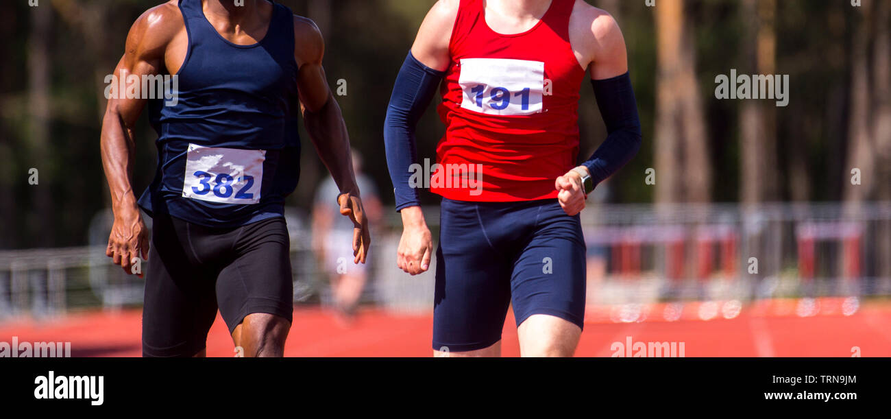 Male athletes sprinting. Two men in sport clothes run at the running ...