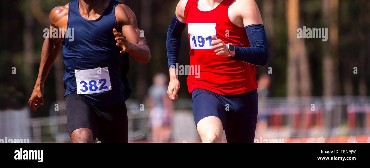 Male athletes sprinting. Two men in sport clothes run at the running ...