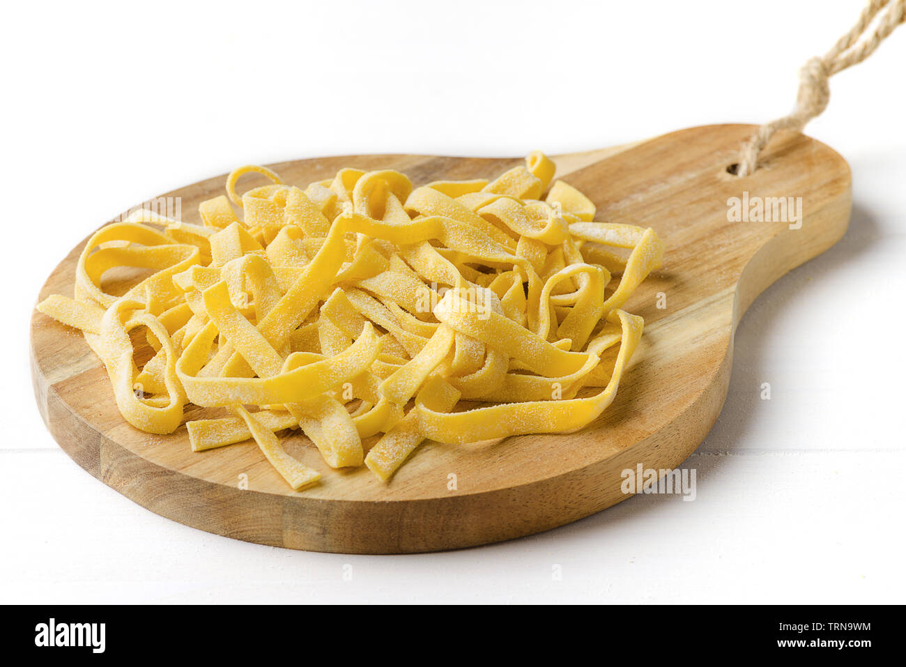 Homemade tagliatelle on cutting board on rustich wooden white ...