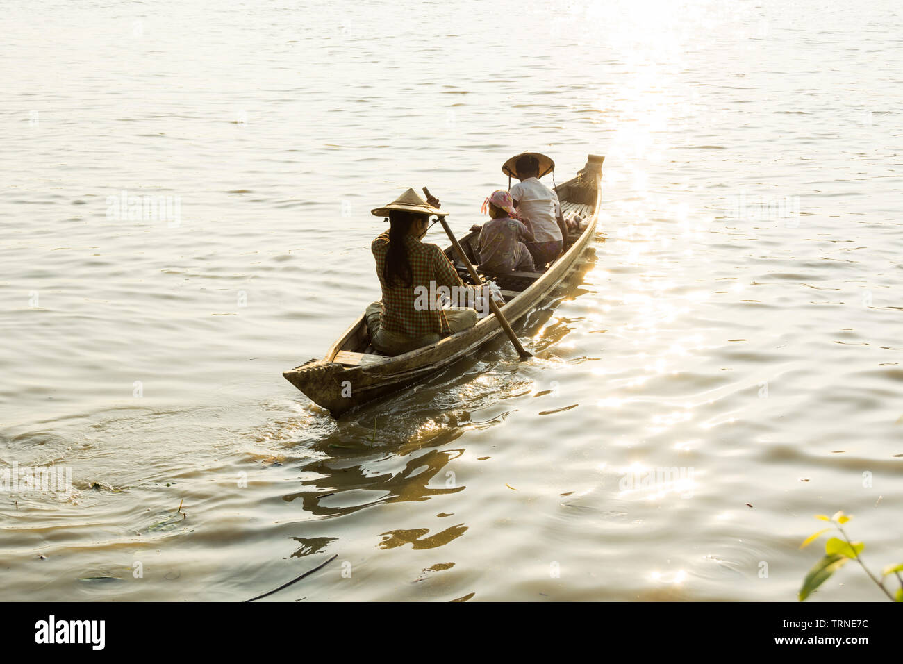 Burmese ladies and a chile crossing river by paddling a small boat 2 ...