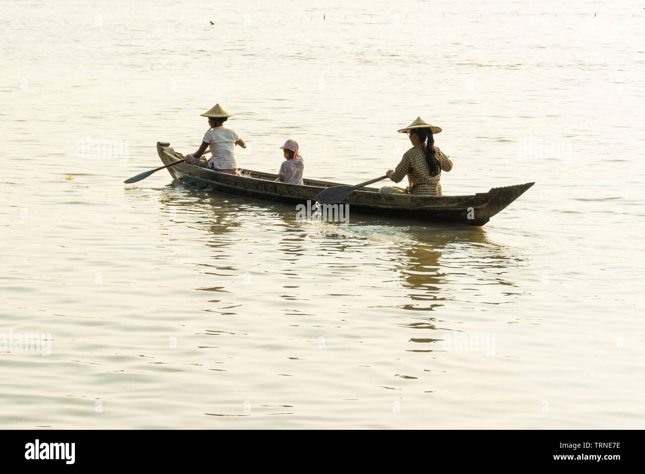 Burmese ladies and a chile crossing river by paddling a small boat 1 ...