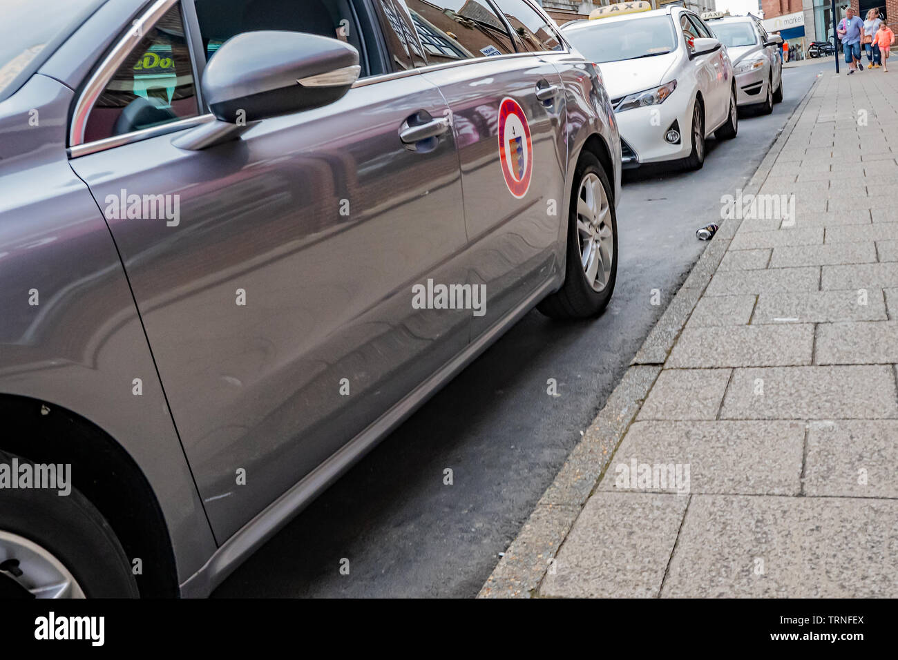 A row of taxi cabs waiting for fares along a shopping street in the ...