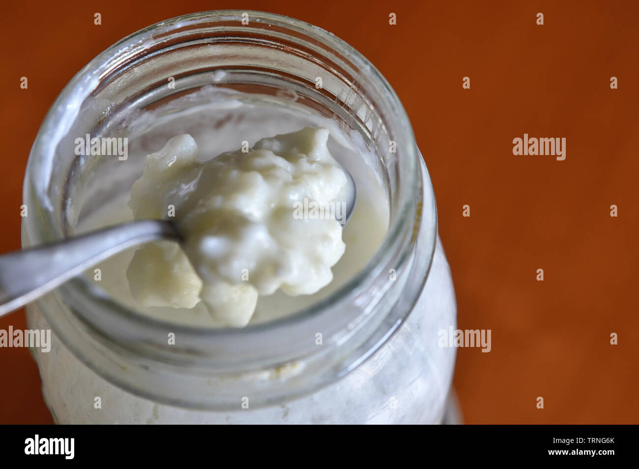 A teaspoon stirs the kefir and raises some granules in a close-up shot ...