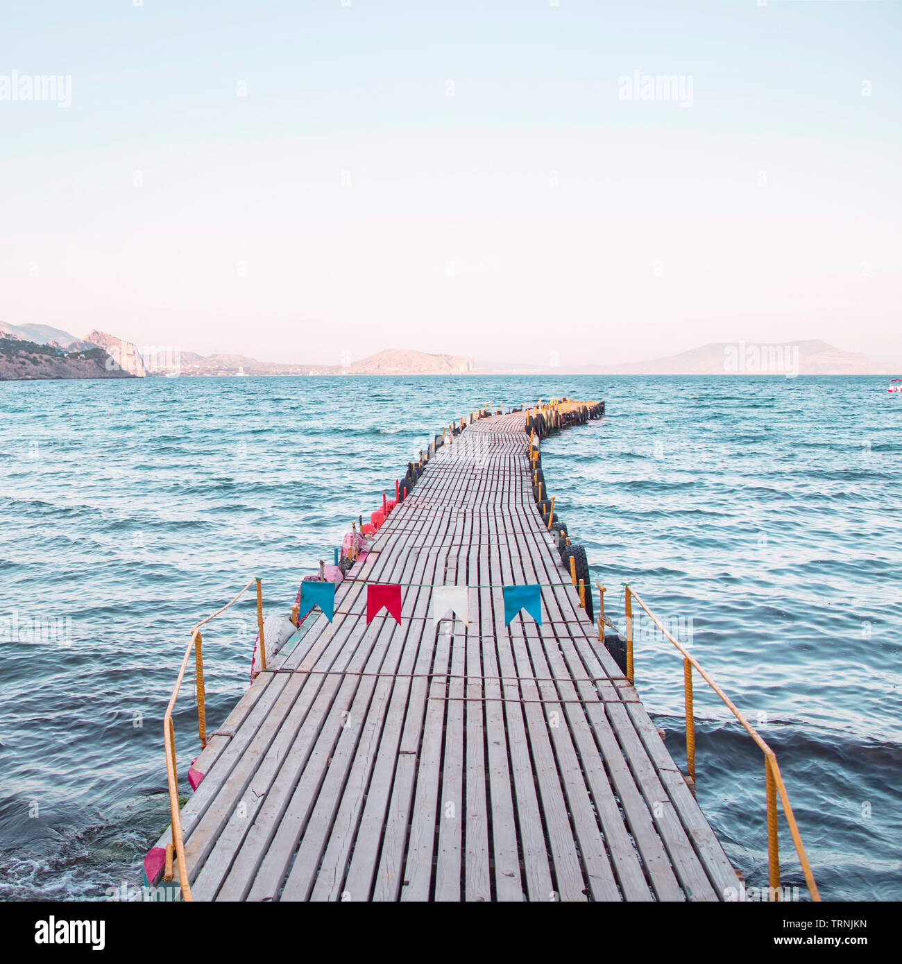 Long wooden pantone that goes deep into the sea. Blue water, clear sky ...