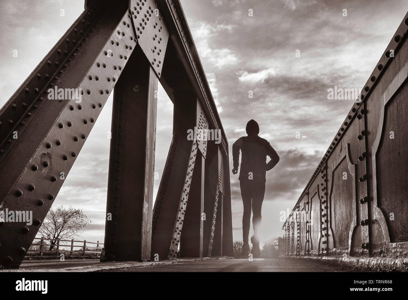 Rear view of man running over bridge at sunrise. UK Stock Photo - Alamy