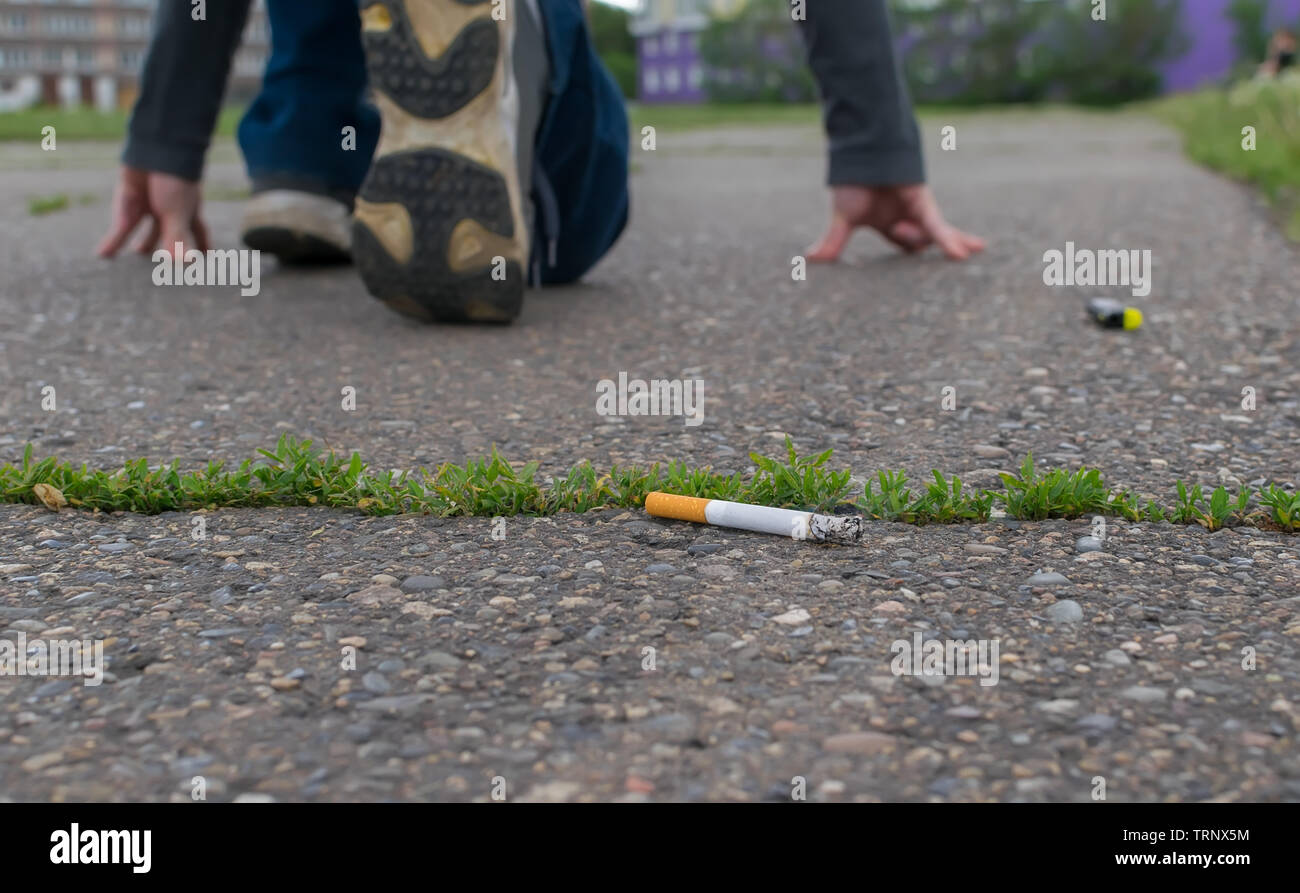 an abandoned Smoking cigarette butt lies on the asphalt path against ...