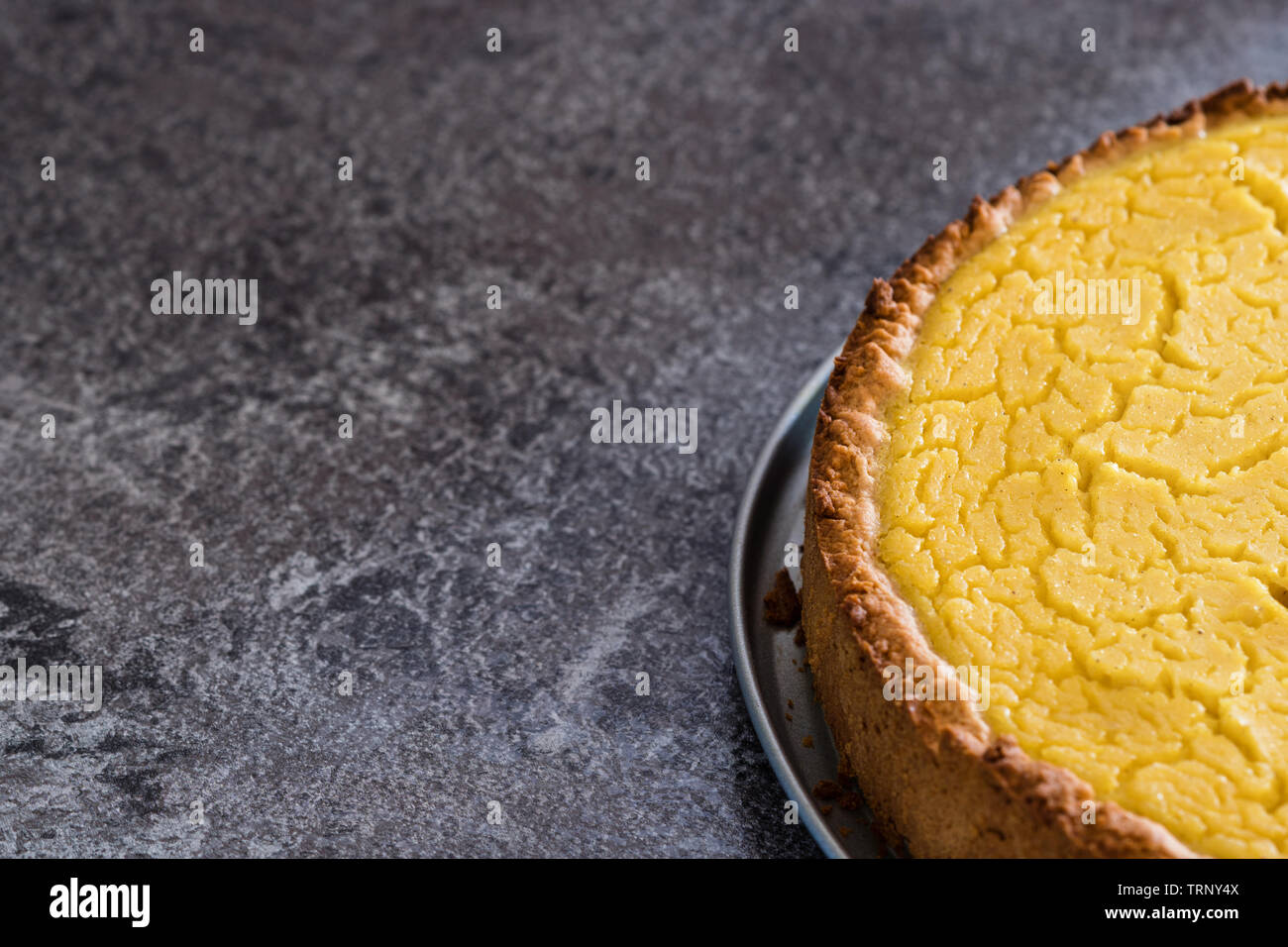 Tasty homemade vegan lemon cheesecake on a plate, dark gray stone ...