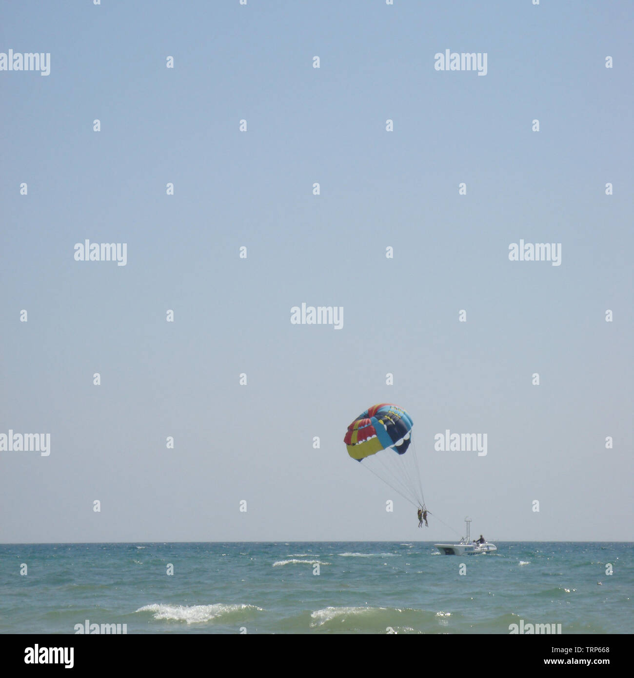 Parasailing over the sea. Flying a tandem paraglider over the sea with ...