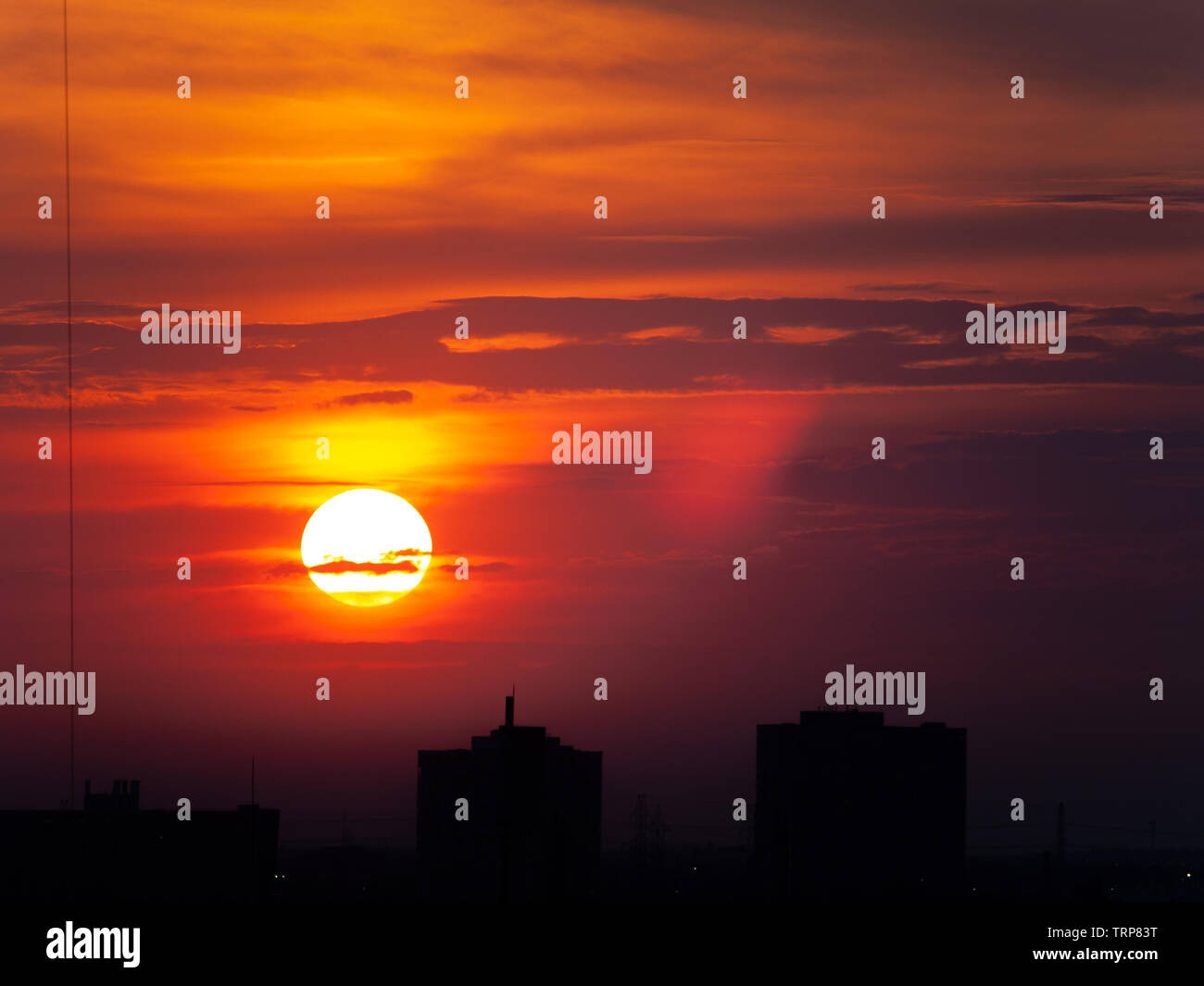 Huge sun setting behind North York buildings, illuminating clouds in ...