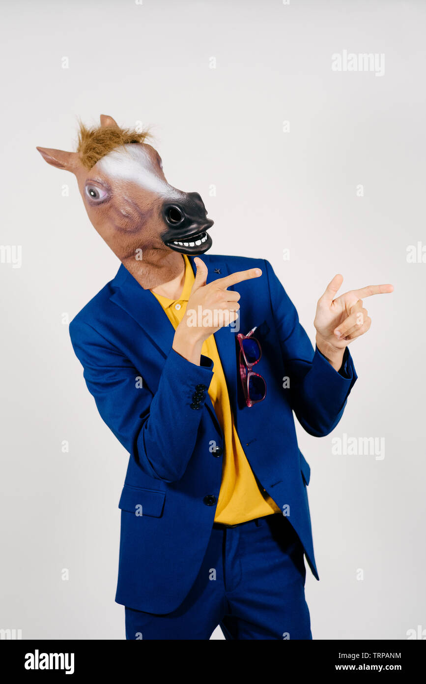 Unrecognizable man disguised with a horse head and dressed with a blue ...