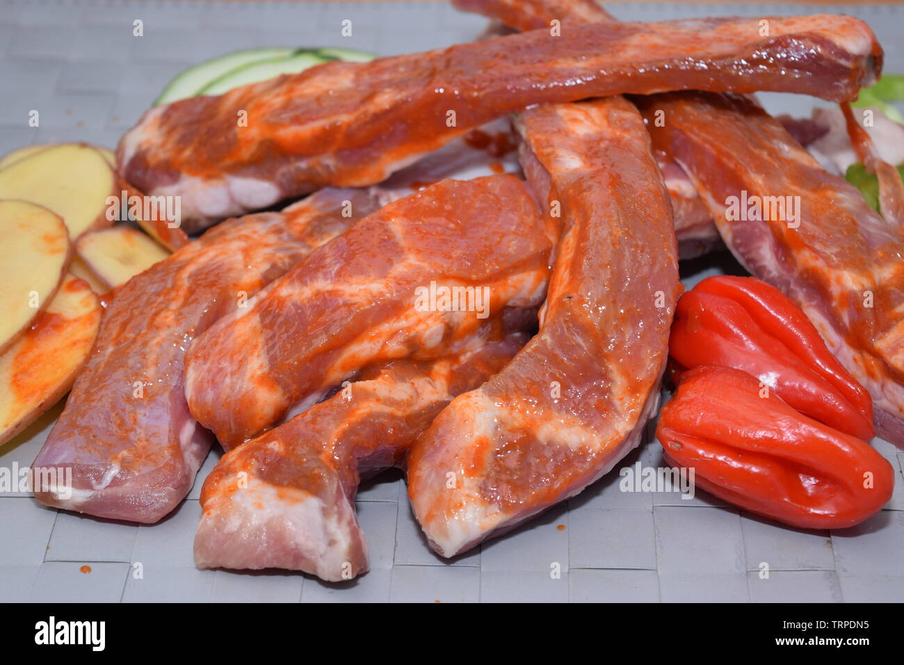 Marinated uncooked pork ribs laid on a clean grey surface with organic ...