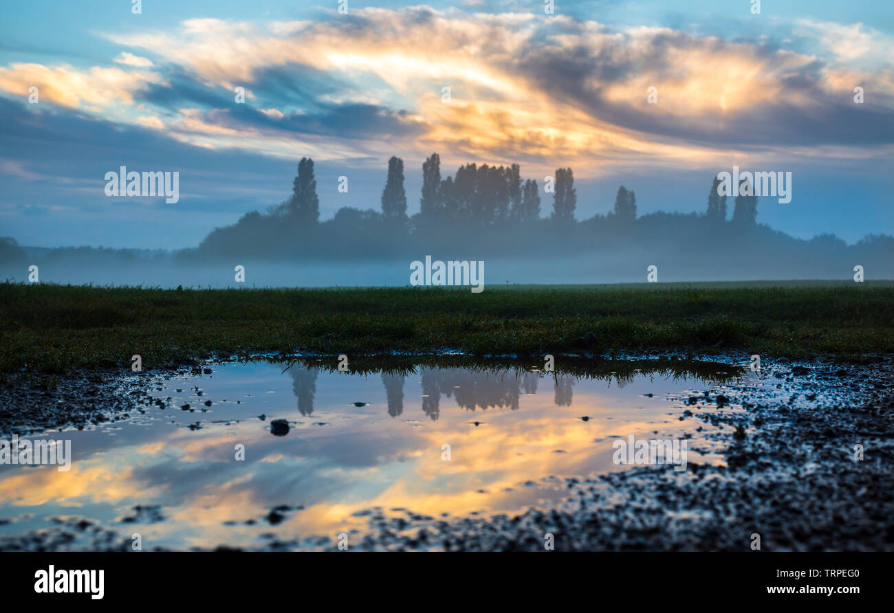 Evening UK sunset sky & water reflection. Atmospheric rising ground ...