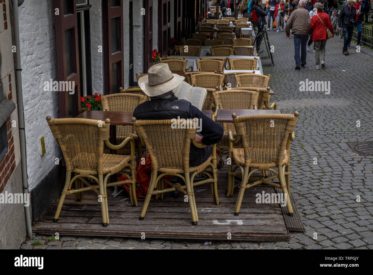 Man sitting outside a cafe reading a book Stock Photo - Alamy