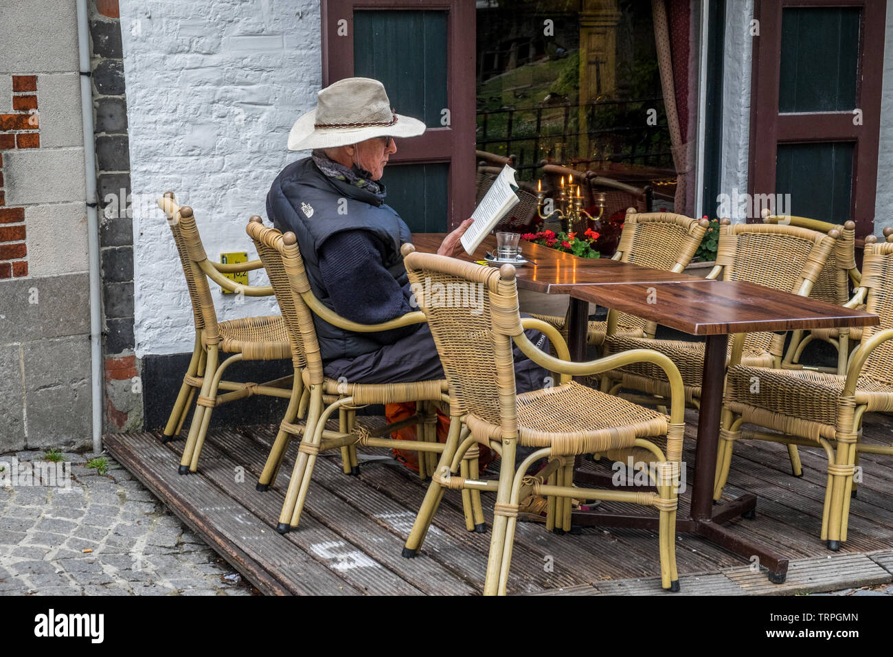 Man sitting outside a cafe reading a book Stock Photo - Alamy