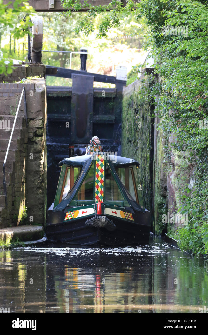 Portrait, front view of isolated UK narrow boat exiting canal lock on a ...