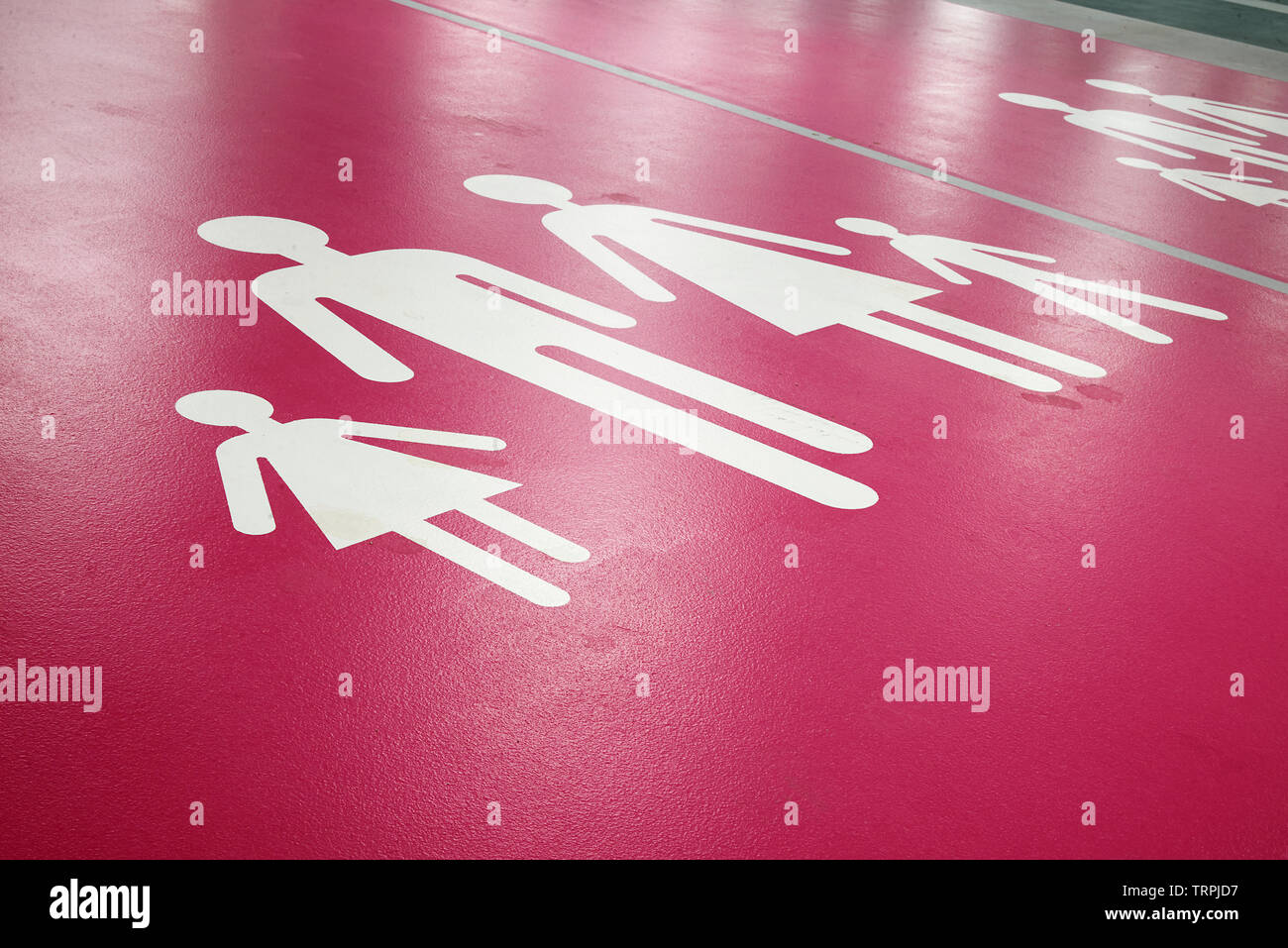 Signage on synthetic pink floor depicting a family of four at an indoor ...
