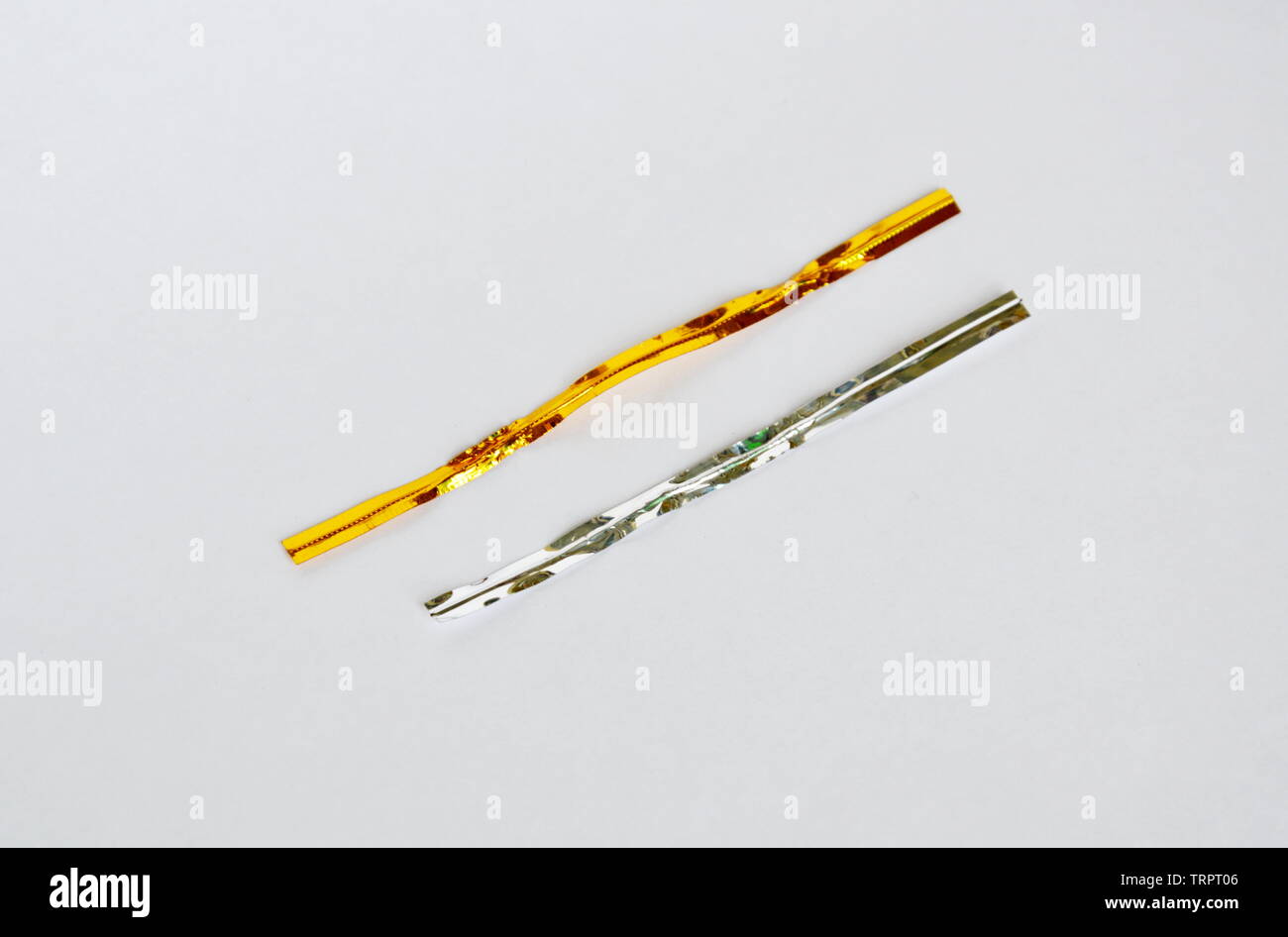 golden and silver twist tie roll on white background Stock Photo - Alamy