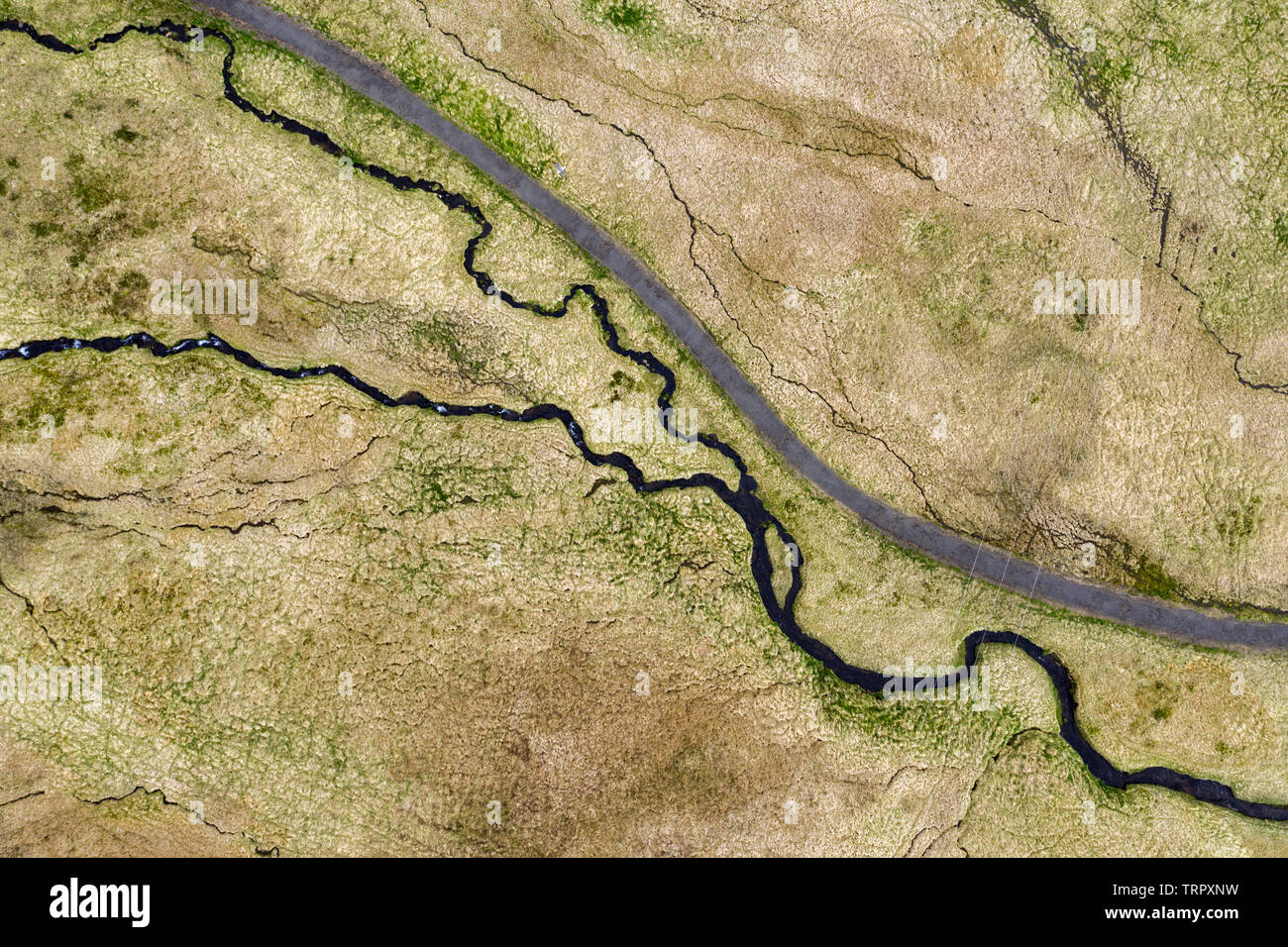 Aerial view of winding small river, stream in green field in Iceland by ...