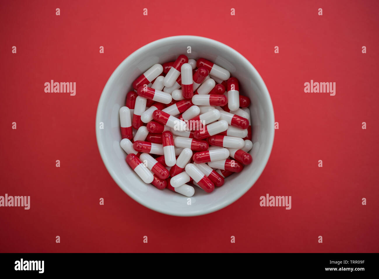 Bowl of drugs pills capsules on red color background Stock Photo - Alamy