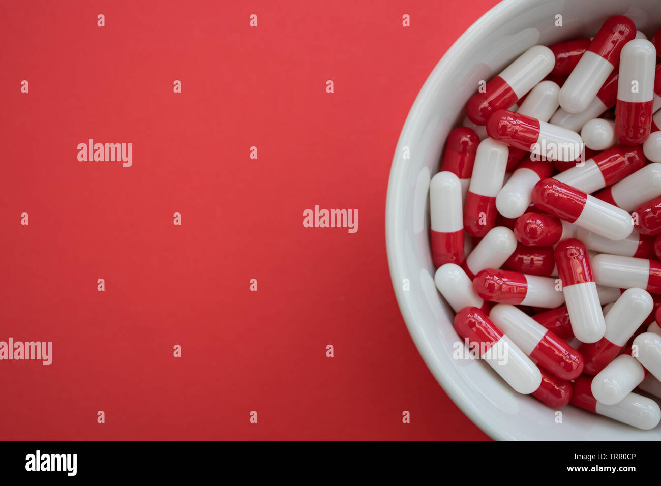 Bowl of drugs pills capsules on red color background Stock Photo - Alamy