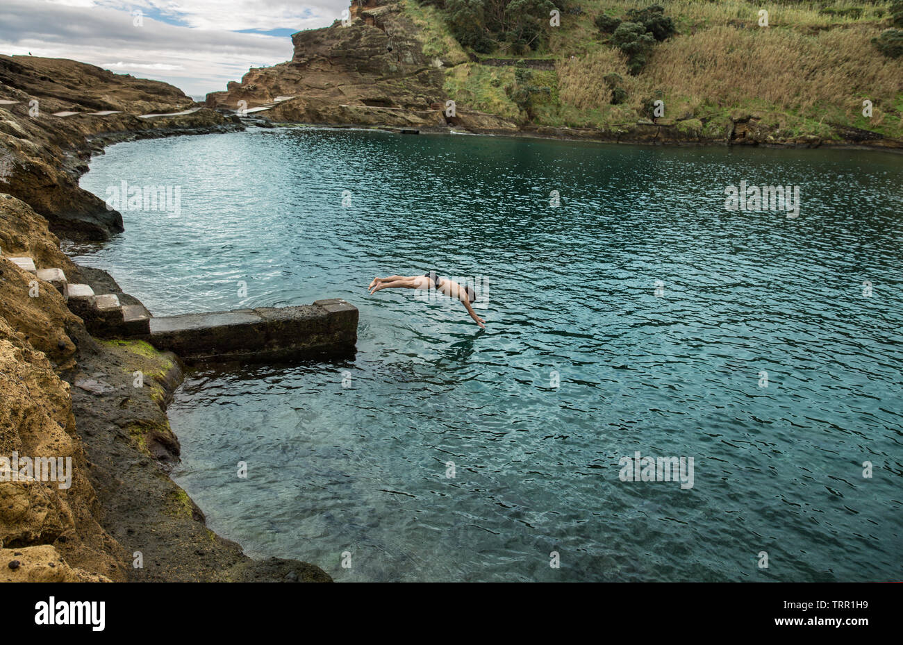Headfirst into water, a man dives from a pier into the atlantic ocean ...
