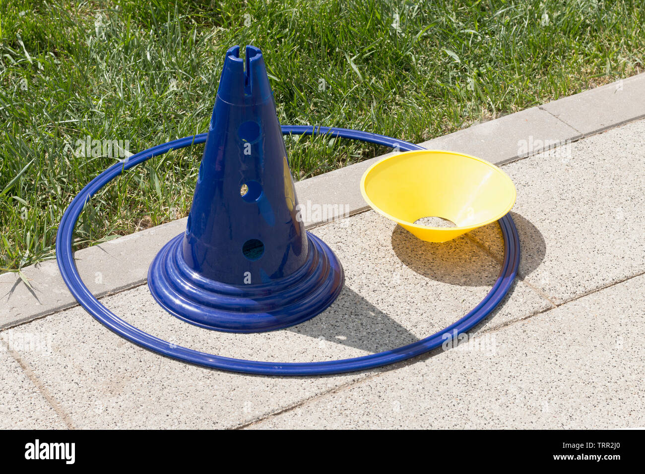 Blue and yellow plastic sport cones with blue hoop on the walkway near ...