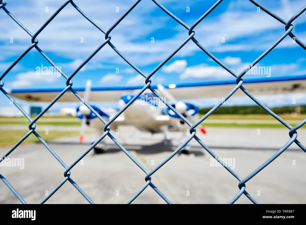 Airplane on runway behind wire mesh fence Stock Photo - Alamy