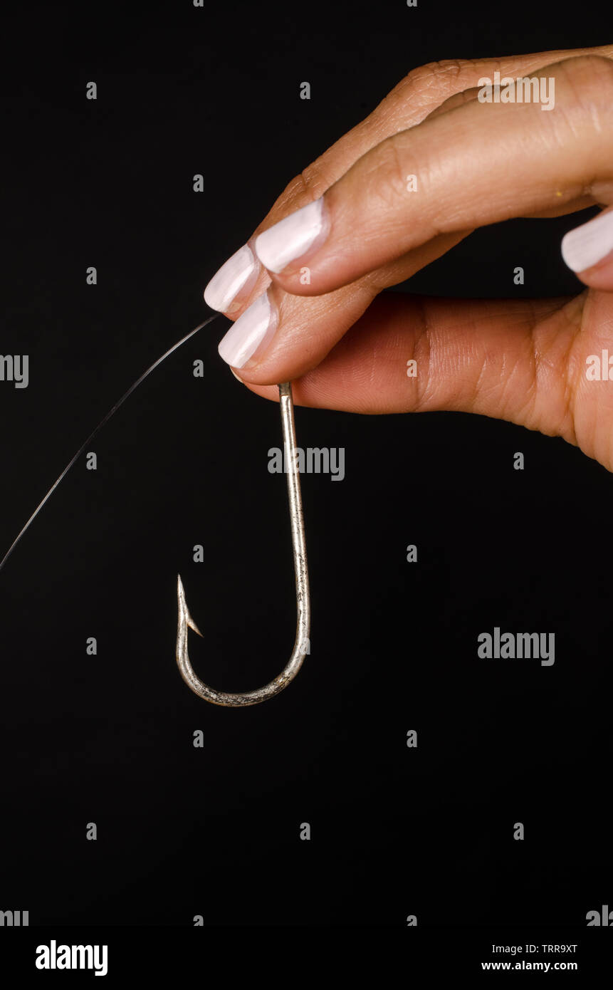 Female hand holding a fishing hook, a conceptual shot on risks and ...