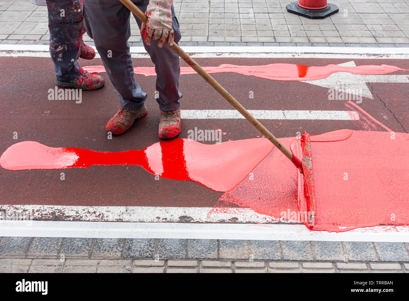 Workman repainting city cycle path Stock Photo - Alamy