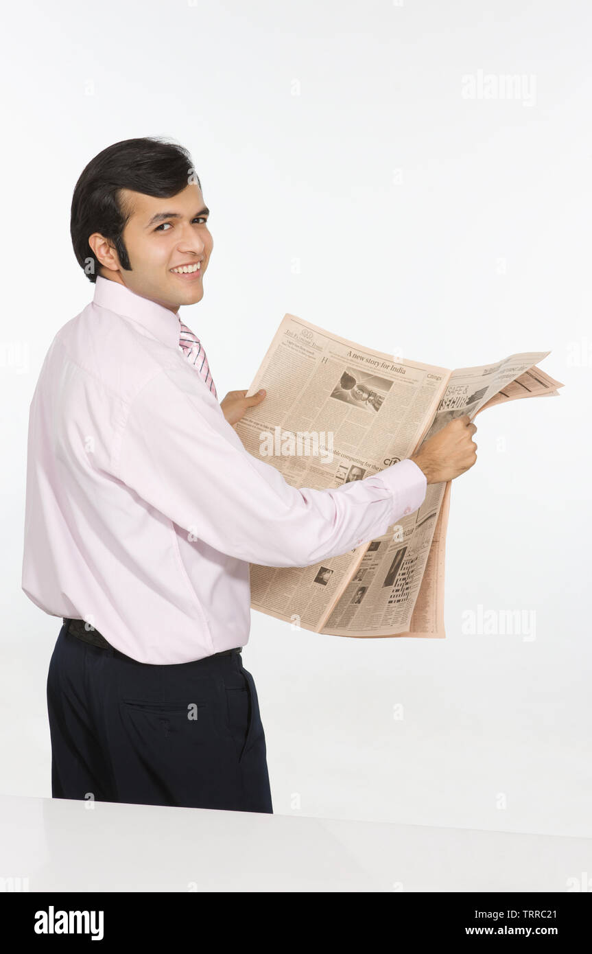 Businessman reading a newspaper and smiling Stock Photo - Alamy
