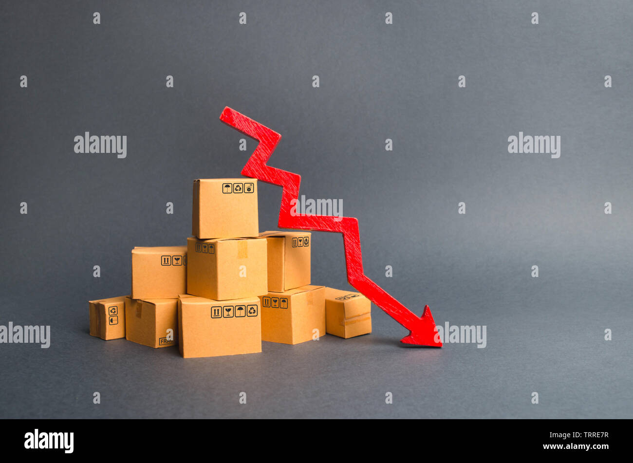 A pile of cardboard boxes and a red arrow down. The decline in the ...