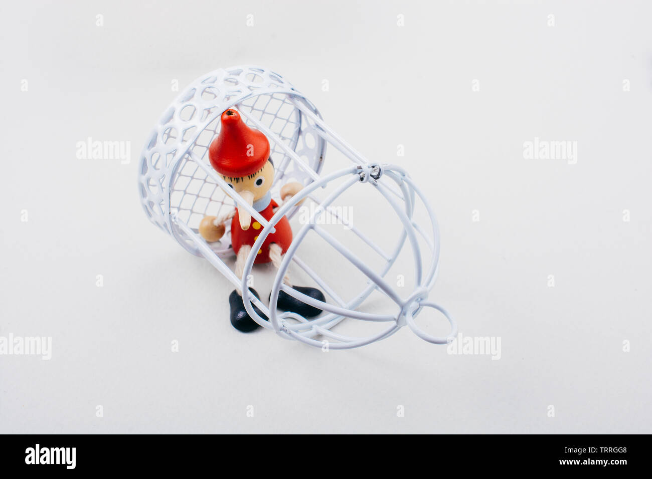 Metal cage and Little puppet pinocchio made of wood Stock Photo - Alamy