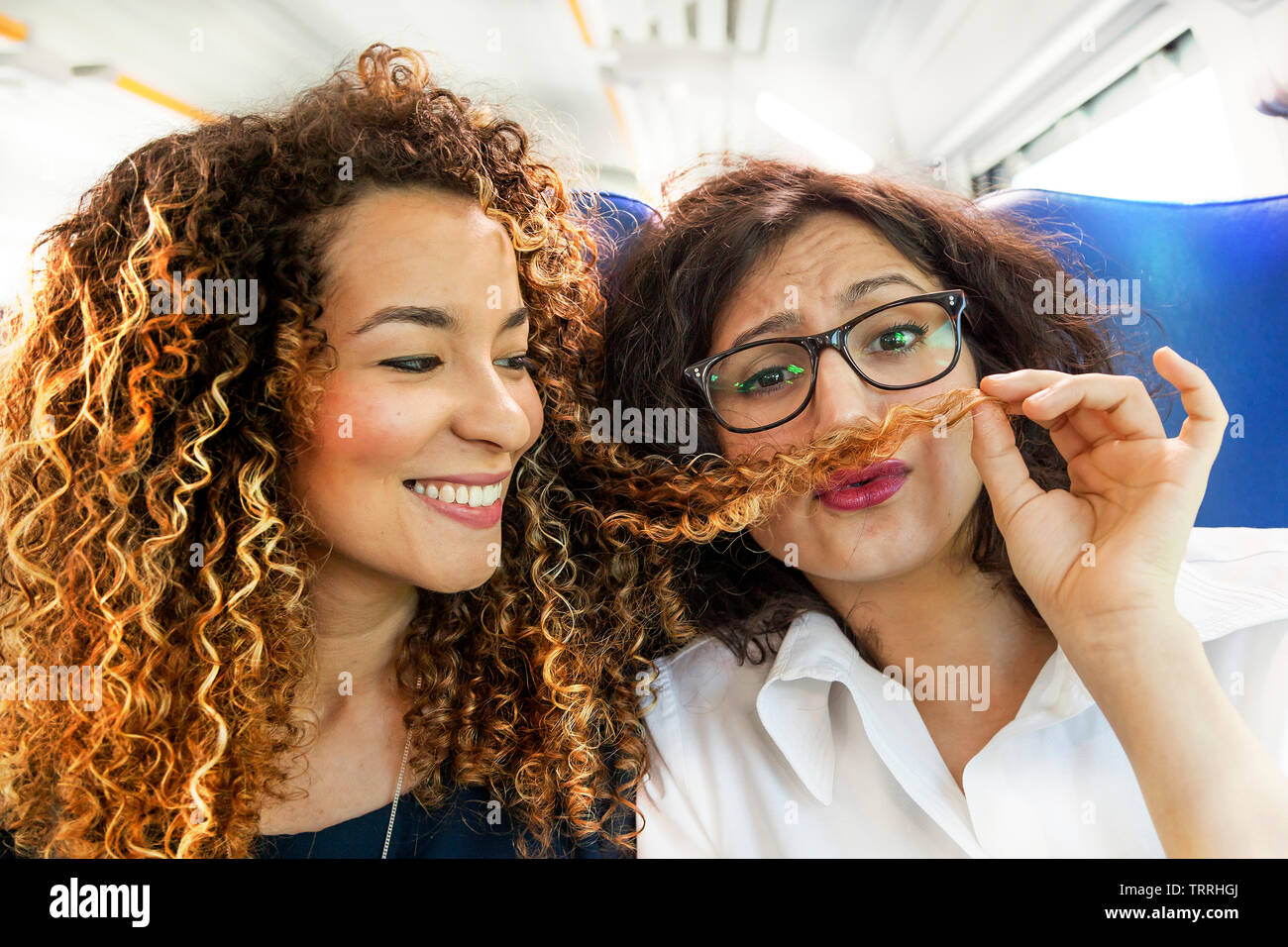 couple of pretty young women having fun with your hair sitting on a ...