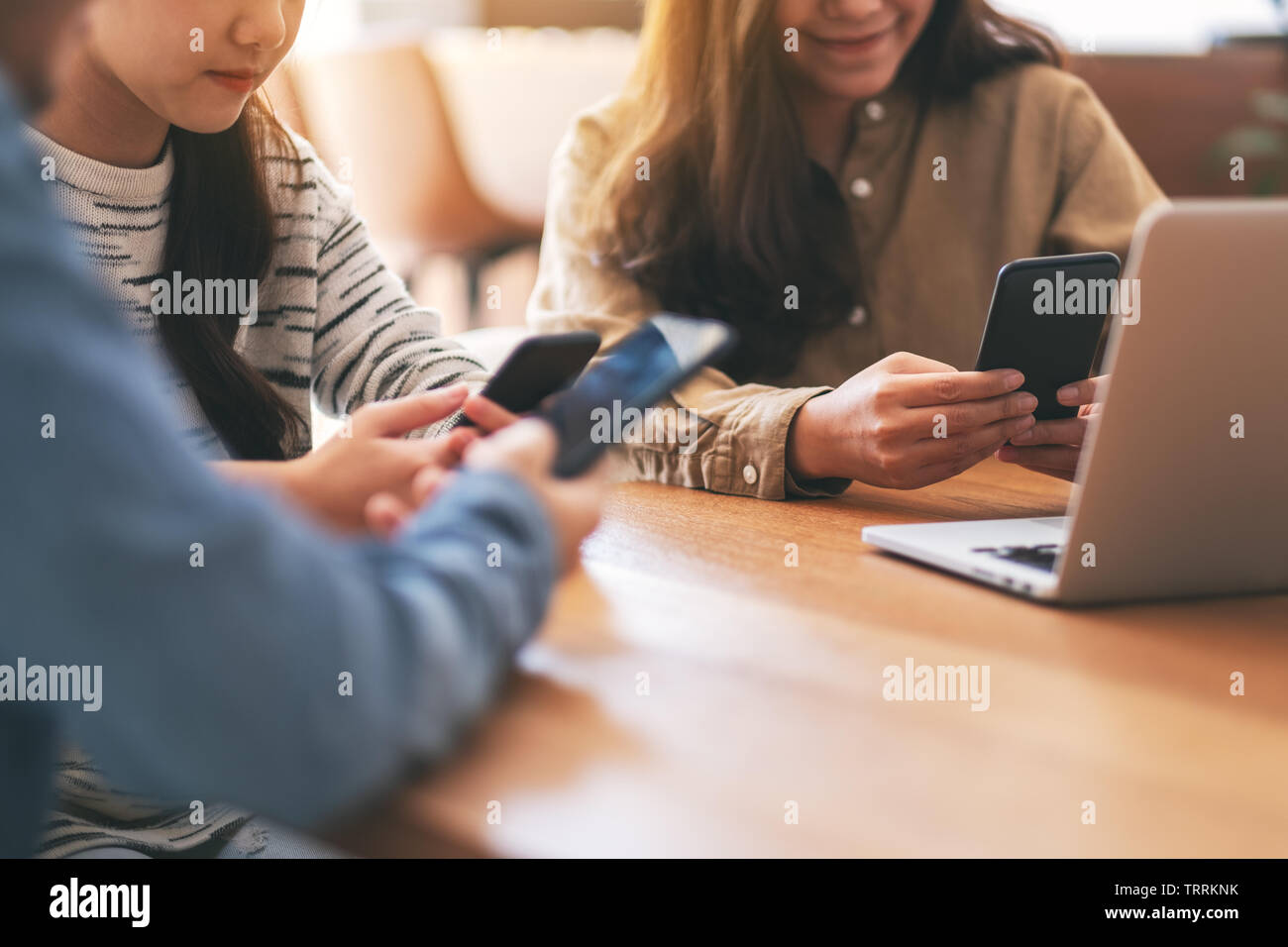 Three young asian people using and looking at mobile phone and laptop ...