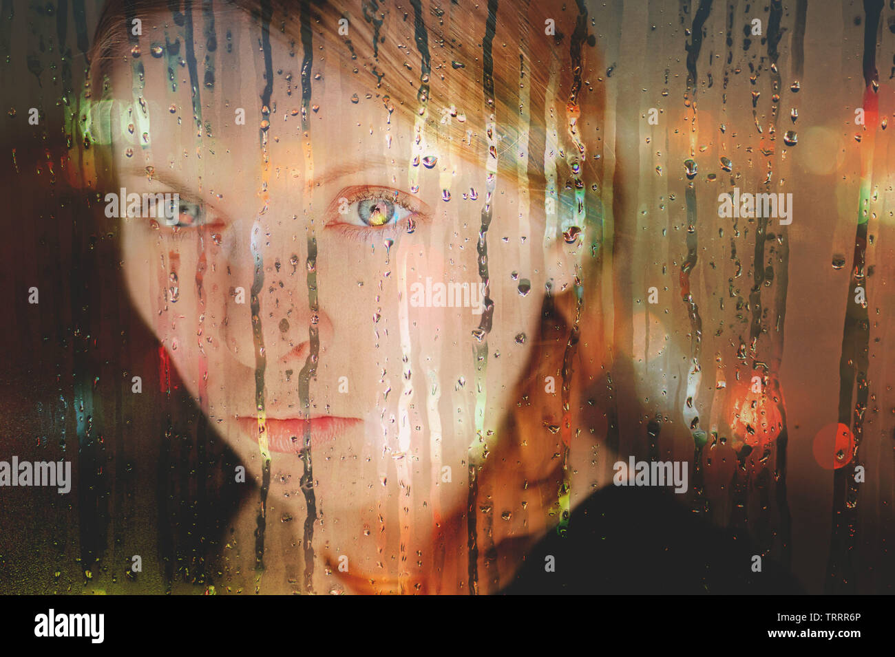 Face of the girl looking through the window. Window drops Stock Photo ...
