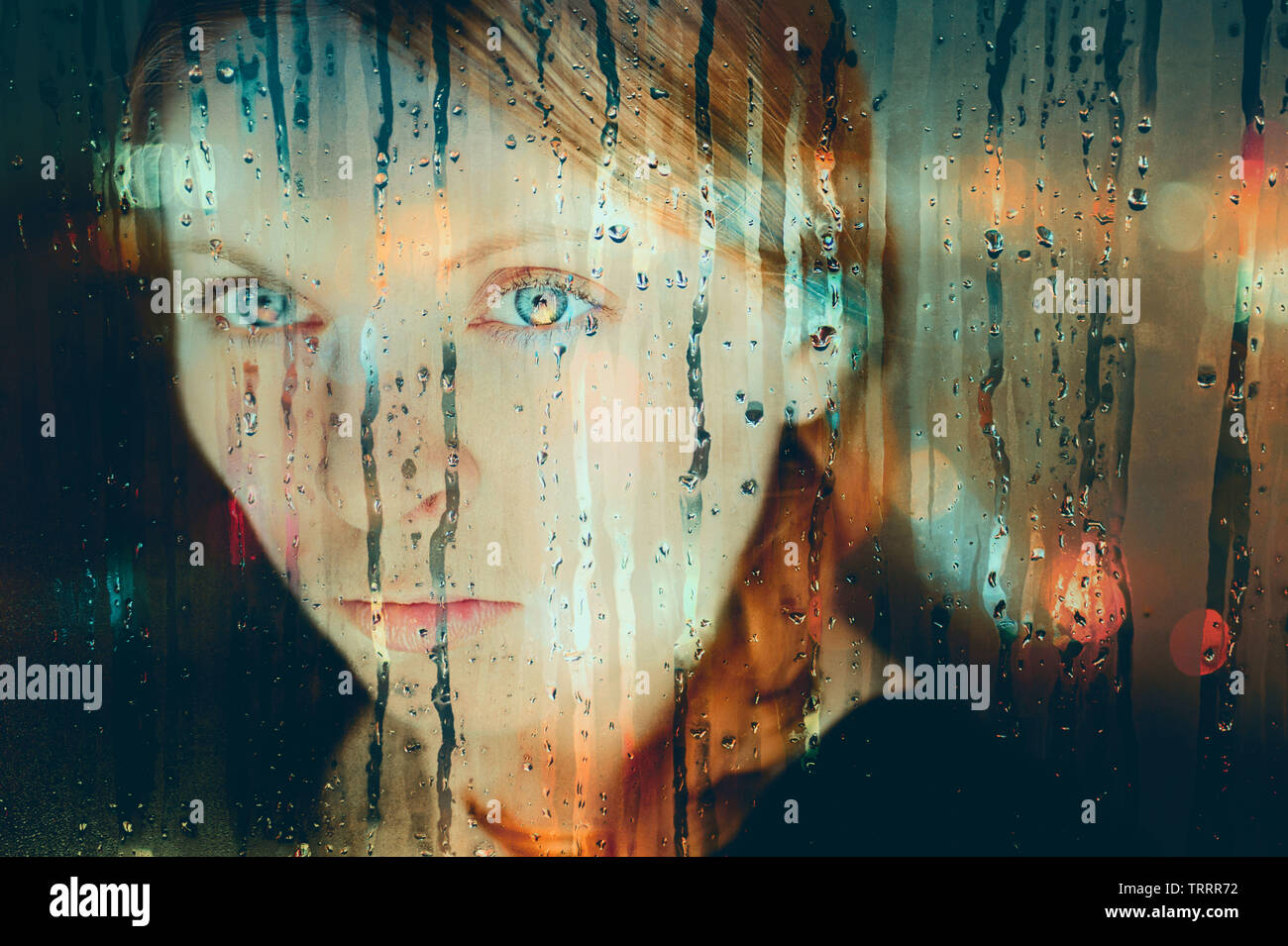 Face of the girl looking through the window. Window drops Stock Photo ...